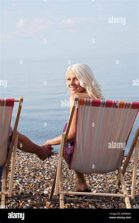Woman Holding Man S Hand Sitting On Deckchair On Beach Stock Photo Alamy