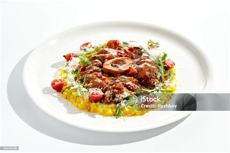 전통적인 이탈리아 요리 리조또 밀라노와 체리 토마토와 루콜라가있는 Osso Buco 흰색 배경에 고립 된 사프란 쌀이있는