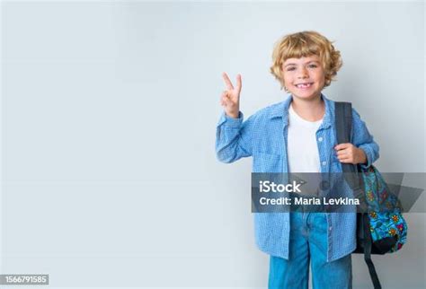 초등학교 웃고 있는 소년 소녀 하얀 배경에 배낭이 있는 승리의 평화 사인 윙크가 카메라에 웃고 있다 빈 개념을 광고하기 위한 공간을 복사합니다 학교로 돌아 가기 어린 시절