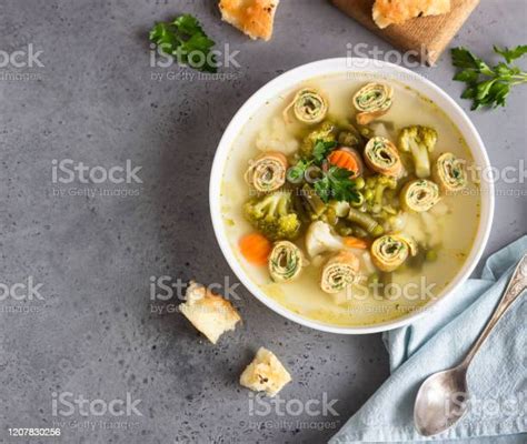 흰 접시에 야채와 달걀 팬케이크를 곁들인 수프 신선한 빵과 파슬리가 밝은 회색 배경에 놓입니다 전통적인 독일 플레들수페와