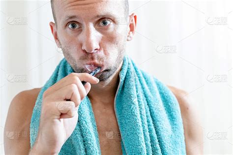 年轻男子的特写与毛巾在他的肩膀上刷牙