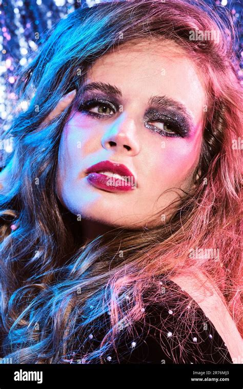 Young Female Model With Colorful Makeup Touching Long Wavy Hair Wearing