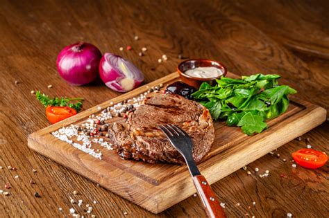 이탈리아 요리입니다 수 분이 많은 쇠고기 고기 시금치 자 두 및 프랑스 겨자 소스와 함께 나무 보드에 송아지 스테이크 테이블에 붉은 석류 와인이 이다 레스토랑에서의 요리