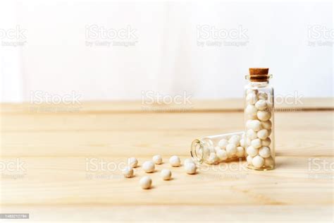 나무 숟가락에 담긴 동종 요법 알약과 나무 테이블 배경에 유봉이 있는 박격포가 있는 병의 개념 동종 요법 의학에 대한 스톡 사진