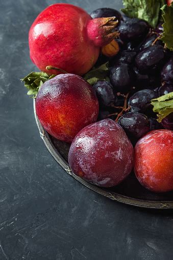 빈티지 접시에 유기 보라색 포도 빨간 매 실 석류 검은 돌 배경 가을 정 수확 유태인 새 해로 시 Hashanah 추수 감사절