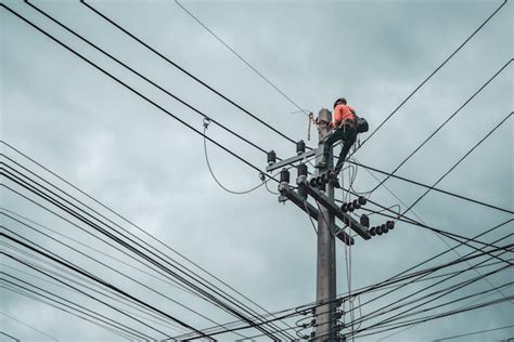 Des électriciens grimpent sur des poteaux électriques pour installer et
