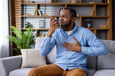 Man Using Asthma Inhaler At Home While Experiencing Breathing Difficulties Stock Image Image