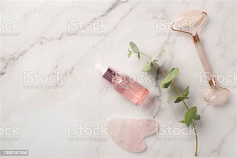 스킨케어 컨셉 장미 석영 롤러 Gua Sha 마사지기 유리 핑크 투명 병의 상단보기 사진 액체 화장품과 유칼립투스 지점이 카피