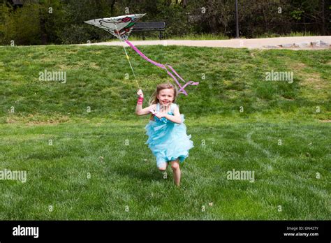 Young Caucasian Girl Laughing As She Runs Trying To Fly Kite Stock