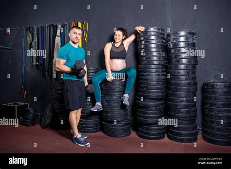 Athletes Pregnant Woman And Her Husband Posing In The Gym Near The