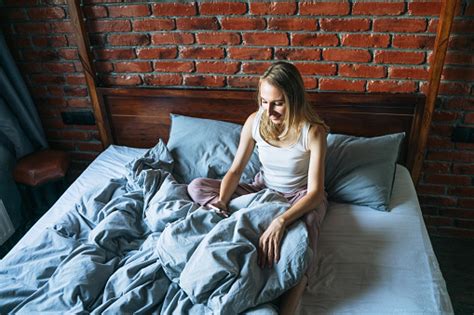 성인 여성 40 세 금발 긴 머리를 사용하여 잠옷에 휴대 전화를 사용하여 집에서 로프트 룸에서 침대에 앉아 40 44세에 대한
