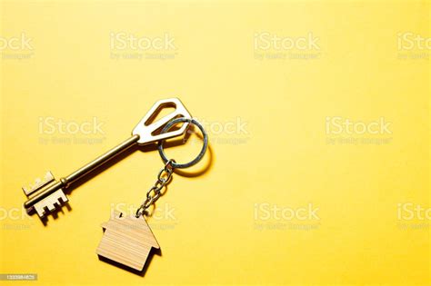 노란색 배경에 키가 있는 목조 주택 모양의 키 체인 건물 디자인 프로젝트 새로운 주택으로 이동 모기지 임대 및 부동산을 구입