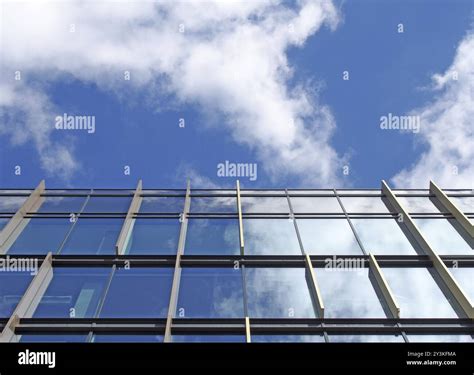 Modern Office Building With Mirrored Glass Windows Reflecting A Bright