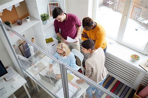 테이블에 앉아 및 현대 사무실에서 동료에 게 정보를 표시 하는 동안 노트북을 사용 하 여 안경에 바쁜 스마트 레이디 프로그래머 계획에 대한 스톡 사진 및 기타 이미지