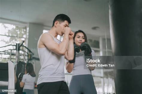 권투 장갑을 끼고 체육관 펀칭 샌드백에서 피트니스 강사로부터 권투 강도 훈련을 배우는 아시아 중국 여자 선수 25 29세에 대한