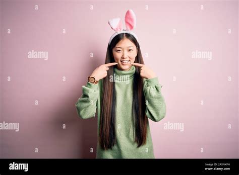Young Asian Woman Wearing Cute Easter Bunny Ears Over Pink Background