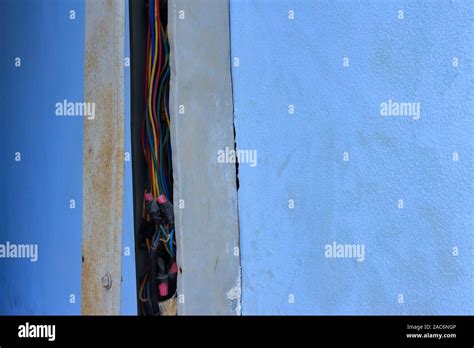 Closeup Exposed Power Lines In Broken Wireway Installed On Dirty Blue