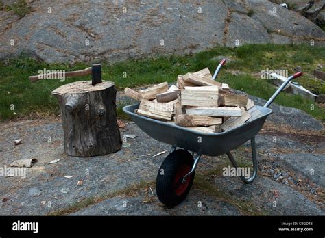Logs In Wheelbarrow And An Axe In Tree Trunk Stock Photo Alamy