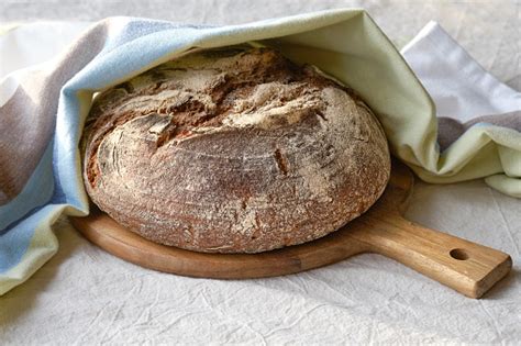 도마에는 반죽한 수제 덩어리가 없습니다 독일어 바우어브로트는 영어로 농부 빵을 의미한다 집에서 세라믹 팬에 구운 통밀 호밀 밀 빵 0명에 대한 스톡 사진 및 기타 이미지