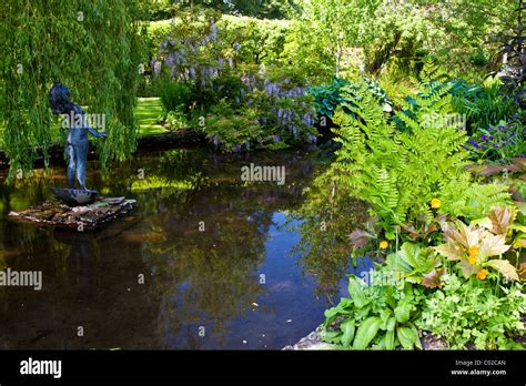 An Ornamental Garden Pond In An English Country Garden With Statue