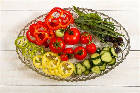 Tamata 오이 양상추 양파와 Arugula 나무 테이블에의 신선한 야채와 야채 샐러드 유리 그릇에 녹색 신선한 야채와 함께