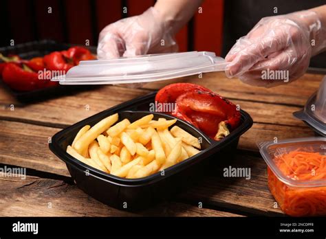 Waiter In Gloves Closing Container With Fresh Prepared Meal At Wooden