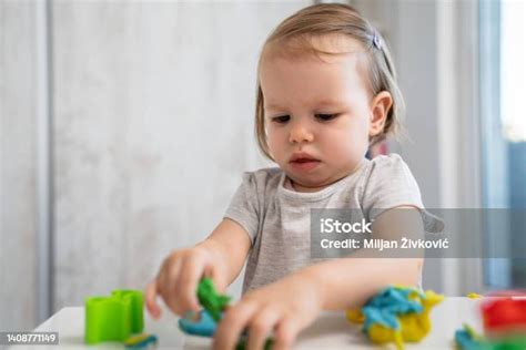 한 소녀 작은 백인 유아 아이가 집에서 혼자 어린 시절에 테이블에 화려한 Plasticine을 가지고 놀고 자라면서 발달 개념