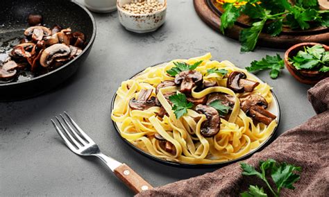 버섯이 있는 맛있는 타글리아텔 파스타는 회색 돌 부엌 테이블 배경에 파슬리와 향신료가 있는 접시에 얹어 최고 전망입니다 건강한