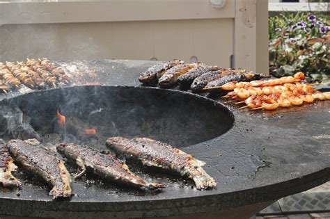 해산물 조각은 원뿔 모양의 그릇 모양으로 화덕 표면에서 조리됩니다 새우 생선 새우를 곁들인 그릇 모양의 플랫 그릴 야외 바베큐 요리 길거리 음식 개념입니다 토스트 뜨거운