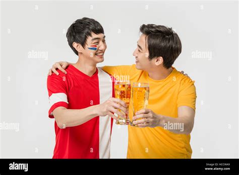 Portrait Of Two Young Smiling Men With Beer Glasses Cheering Stock