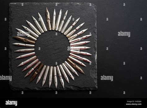 Steel Dip Pen Nibs Arranged In A Circle Isolated On Black Stone Tile