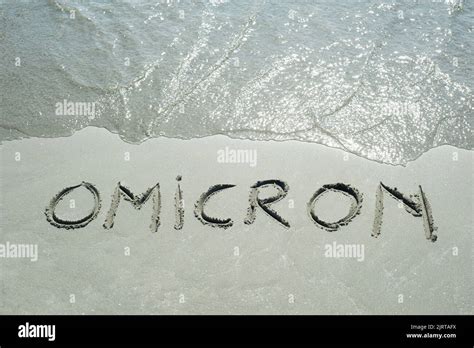 Concept Or Conceptual Omicron Text Handwritten In Sand On A Beach With Waves In An Exotic Island