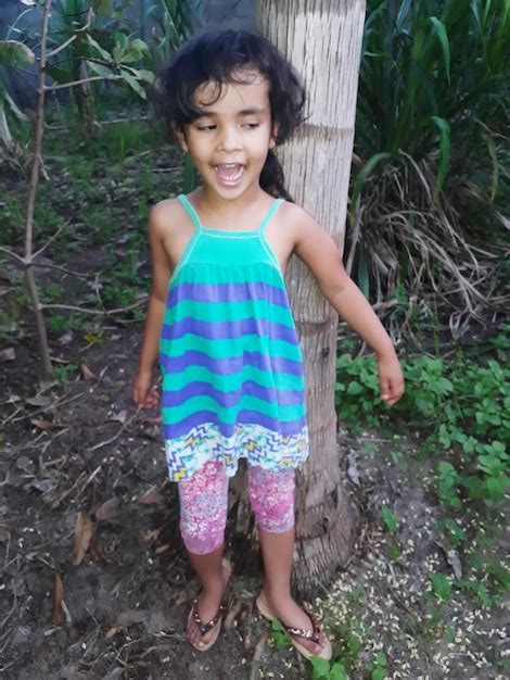 Niña Con La Boca Abierta De Pie Contra El Tronco Del árbol Foto Premium