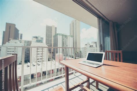 窓際のテーブルに置かれたノートパソコン Photos Adobe Stock