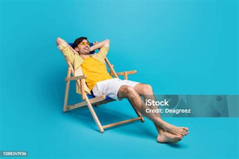 전체 길이 프로필 측면 사진 의 긍정적 인 사람 여행자 휴식 해변 일광욕 거짓말 편안한 갑판 의자 스트레칭 손 은 파란색 배경에 고립 된 흰색 반바지를 착용 휴식에 대한