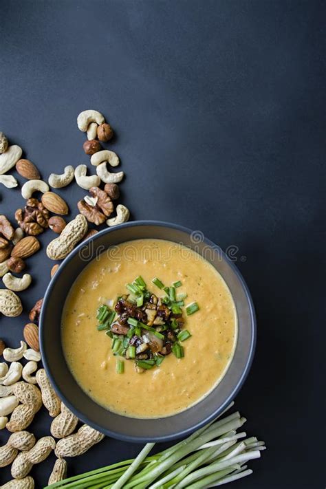 Pumpkin Cream Soup With Herbs And Nuts Served In A Dark Bowl Proper