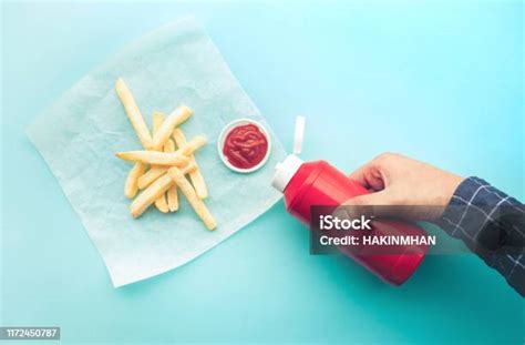 블루 컬러 배경에 프렌치 프라이드와 함께 찍어 주먹으로 병 소스 를 짜내는 젊은이의 탑 뷰 감자 요리에 대한 스톡 사진 및 기타