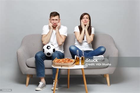 흰색 T 셔츠에 관심 슬픈 부부 여자 남자 축구 팬 회색 벽 배경에 고립 된 축구 공을 좋아하는 팀 지원 응원 사람들의 감정 스포츠 가족 레저 라이프 스타일 개념입니다