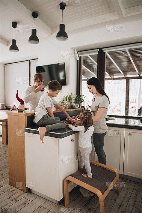 这家人在厨房里做姜饼。爸爸，妈妈，儿子，女儿，兄弟姐妹。揉面，切饼机，新年，圣诞节，节日晚餐。灰色的