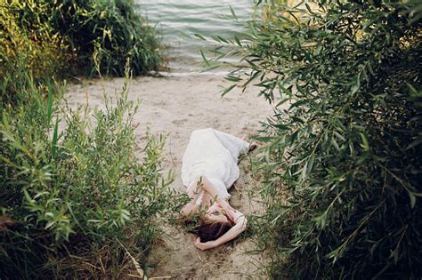 호수 근처 일몰 빛 모래 해변에 누워 아름 다운 Boho 소녀 바람 머리 녹색 잎 사이에서 물에 가까운 편안한 화이트 보헤미안