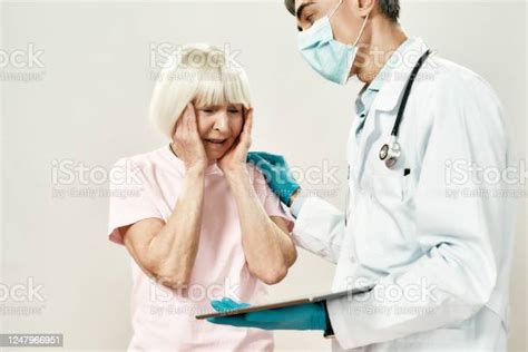 진단을 설명하는 의료 유니폼 및 보호 마스크전문 남성 의사를 듣고 슬픈 노인 여성 환자 2명에 대한 스톡 사진 및 기타 이미지