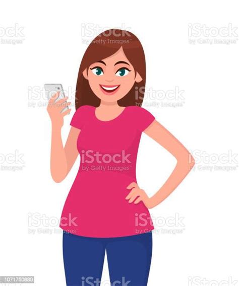 아름 다운 젊은 여 자가 엉덩이에 손을 잡고 흰색 배경에 서 있는 하는 동안 스마트 휴대 전화를 들고 웃 고 현대적인 라이프