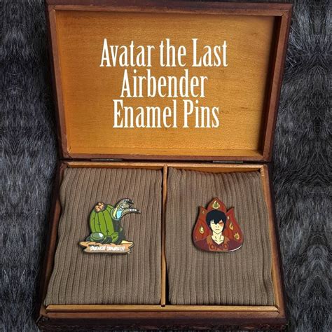 Two Lapel Pins In A Wooden Box With The Words Avatar The Last Airbender