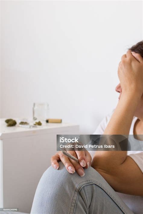 마약 중독에 걸린 알아볼 수 없는 여성이 새싹 옆에 대마초를 손에 들고 있습니다 마리화나 흡연의 개념세로 이미지 50 54세에