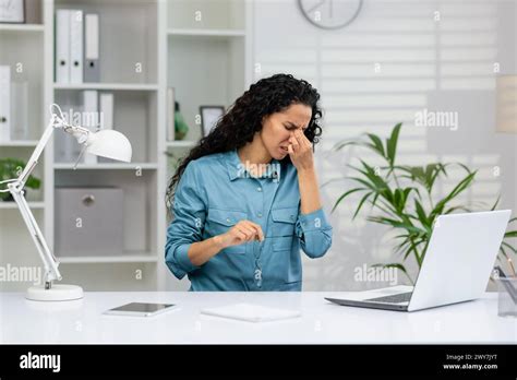 a professional businesswoman looks stressed and tired rubbing her temples to relieve a headache