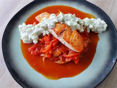 A White Plate Topped With Meat Covered In Sauce And Mashed Potatoes On