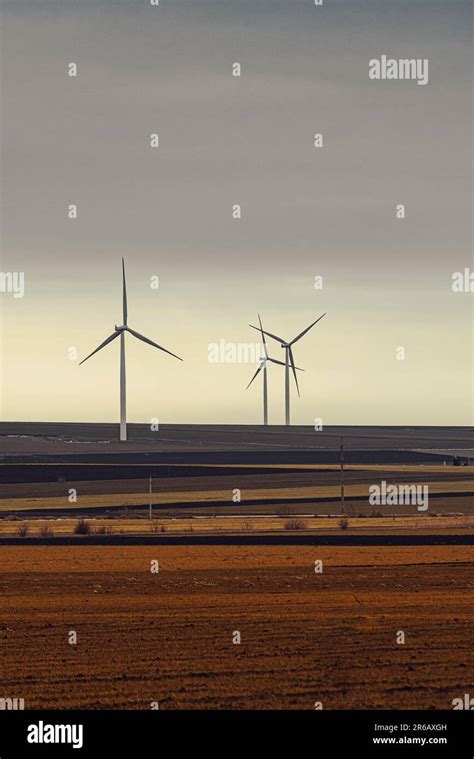 Three Wind Turbines Standing In An Expansive Grassland Surrounded By An Expansive Empty