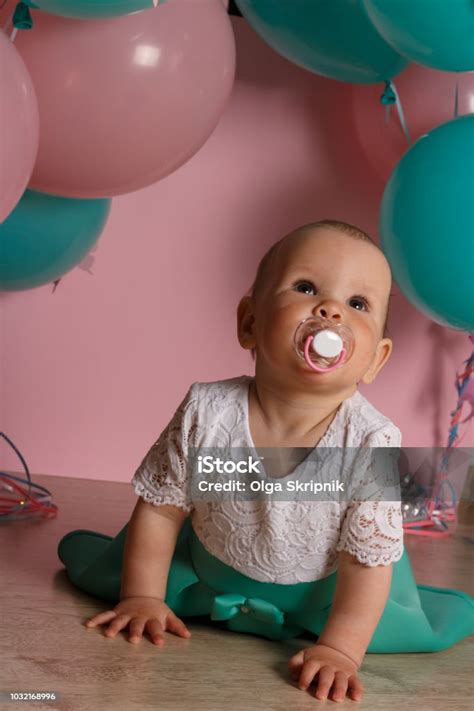 어린 소녀는 젖꼭지와 분홍색 배경 풍선 근처에 바닥에 앉아 있다 축 하입니다 생일 한 살입니다 노리개와 작은 소녀 공주에 대한 스톡 사진 및 기타 이미지 Istock