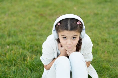 기술은 당신의 가장 친한 친구가 될 수 있습니다 녹색 잔디에 스테레오 사운드 기술을 즐기는 작은 아이 어린 소녀는 여름 자연에