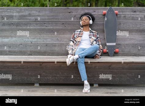 Young Skateboarder Girl Chilling Listen To Music Closed Eyes On Bench